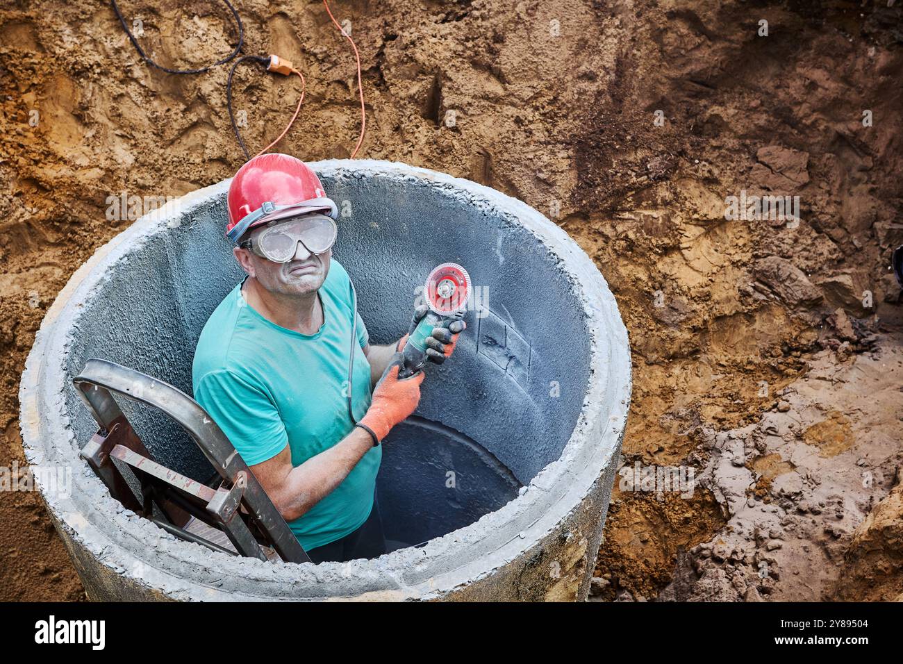 Cement dust blinded septic tank builder as he sawing hole in concrete ...