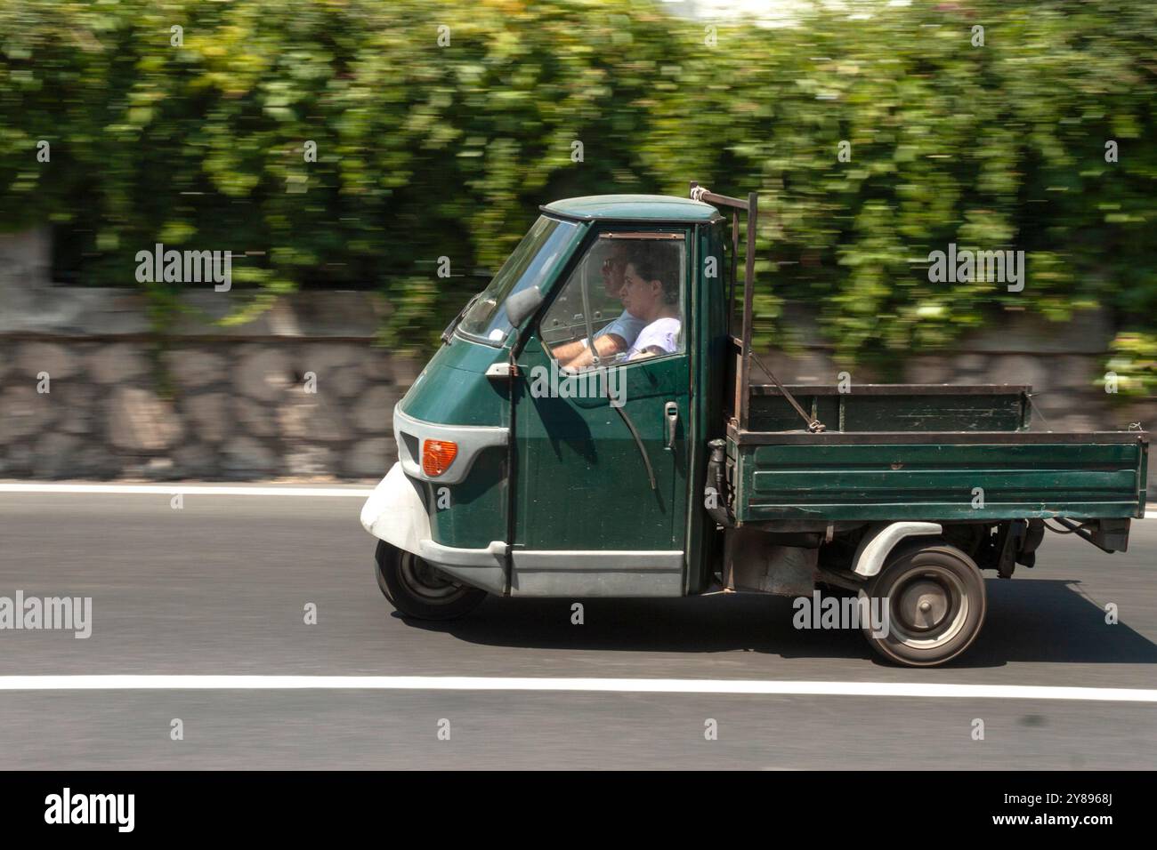 old green piaggio ape utility vehicle panning shot driving in sorrento ...