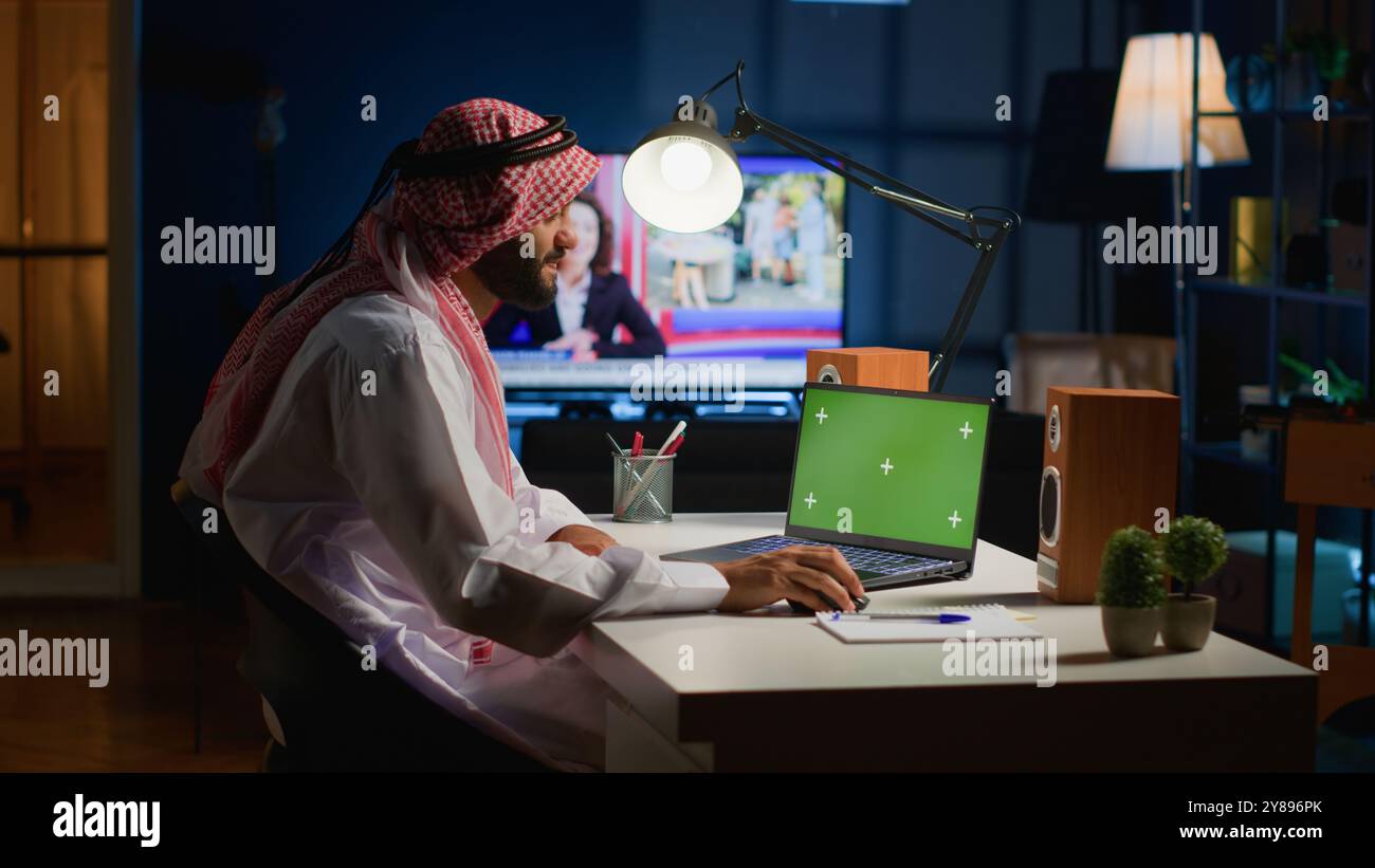 Arab remote worker inputting data on mockup laptop while working from ...