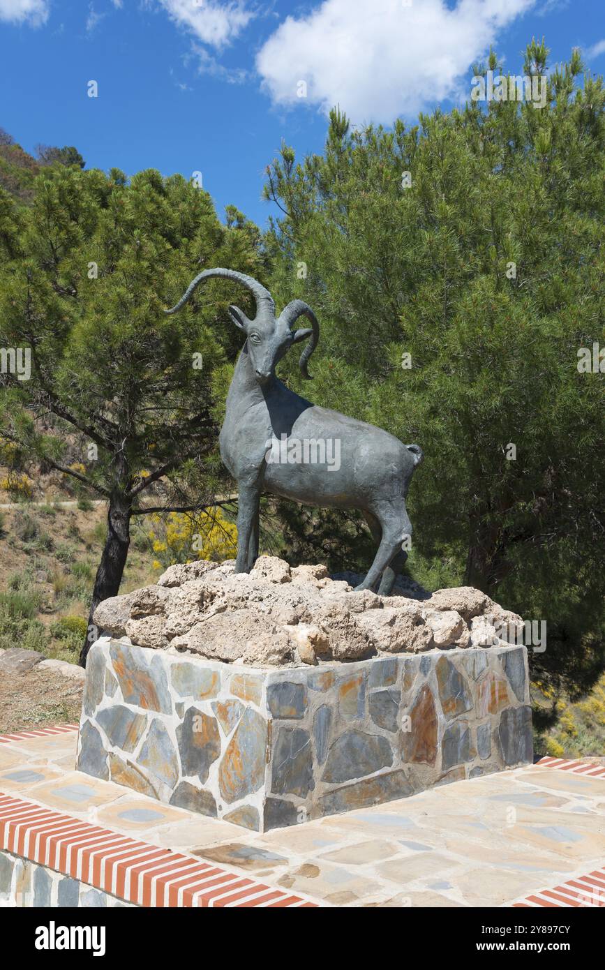 Bronze ibex statue on a brick base surrounded by green trees, Area ...