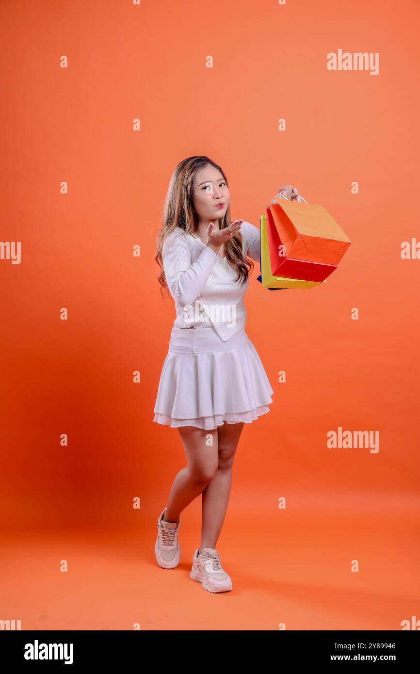 full body charm asian woman white top standing kiss look at camera hand lifting shopping bag ...