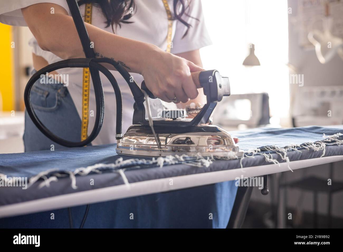 A woman dressmaker steams and irons fabric for cutting and sewing ...
