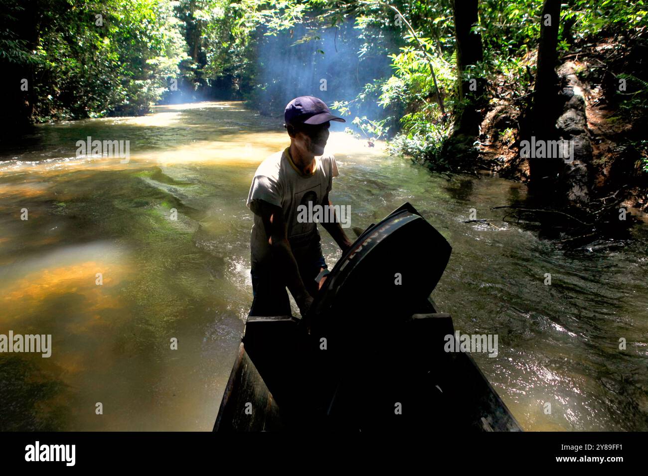 A boat motorist pushing the boat to move on shallow water in the river ...