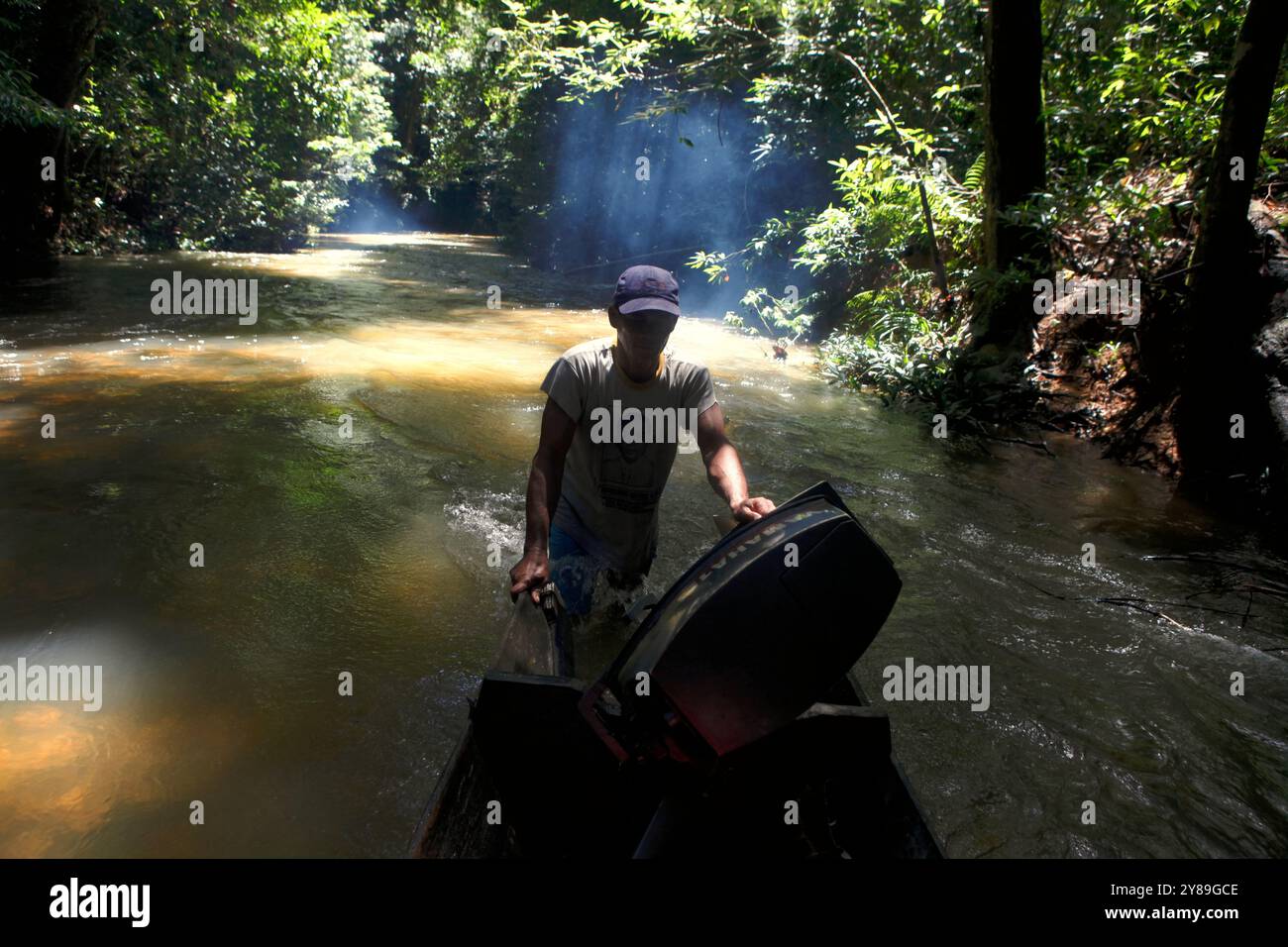 A boat motorist pushing the boat to move on shallow water in the river ...