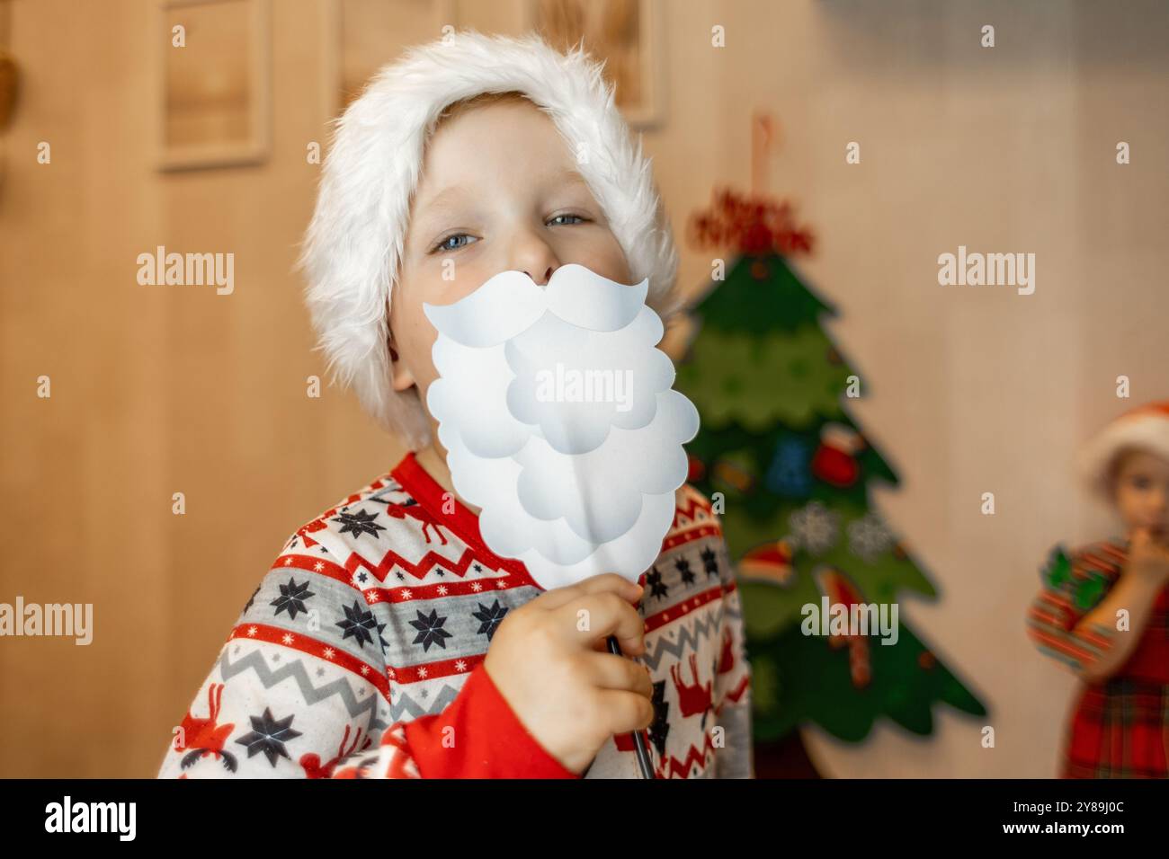 A young child wearing a festive outfit and a fluffy hat playfully poses ...