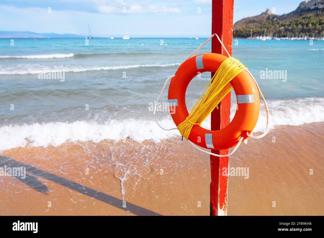 Lifebuoy with rope mounted on a pole on the beach. Life preserver ...