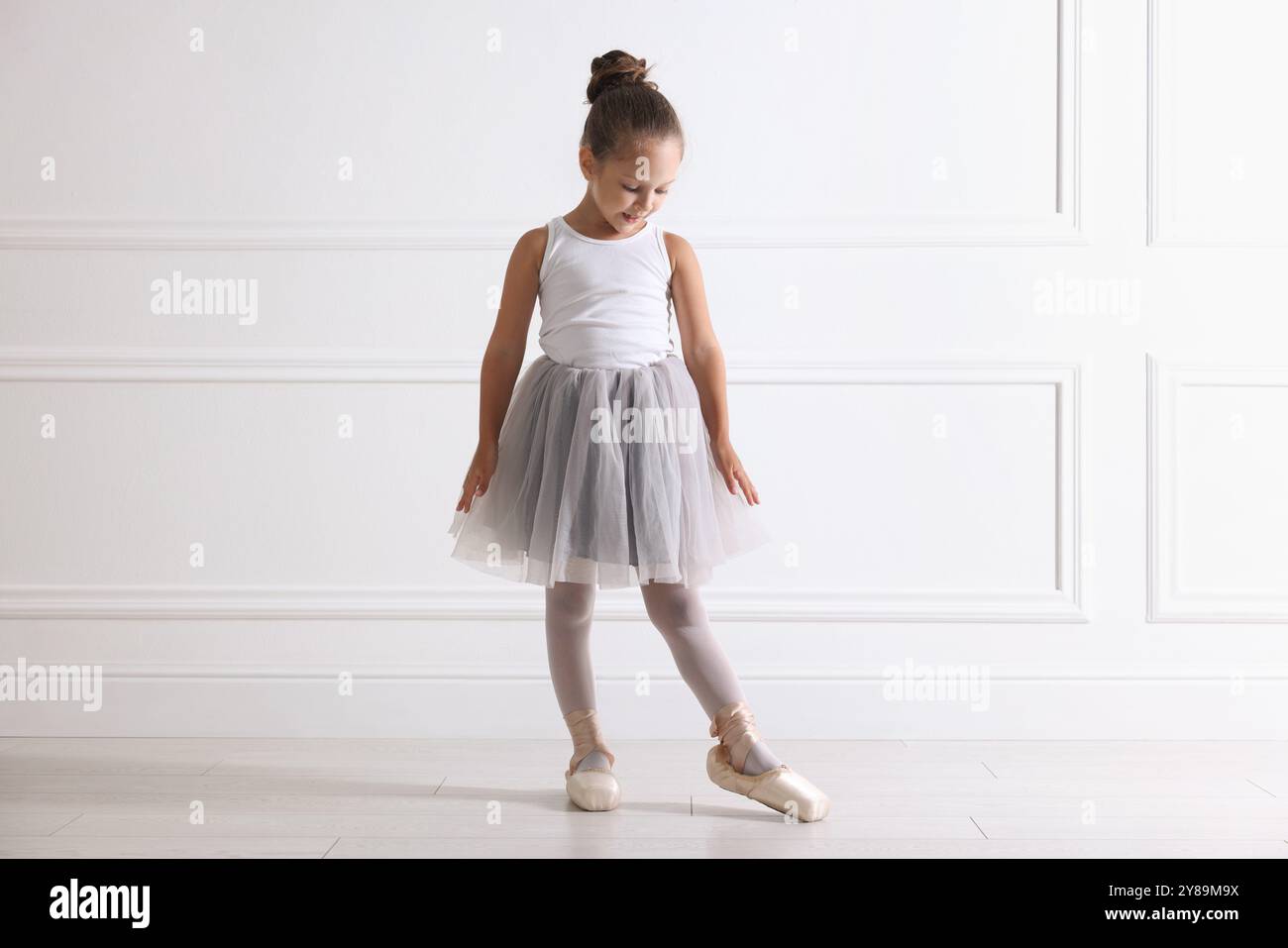 Little ballerina practicing dance moves near white wall indoors Stock ...