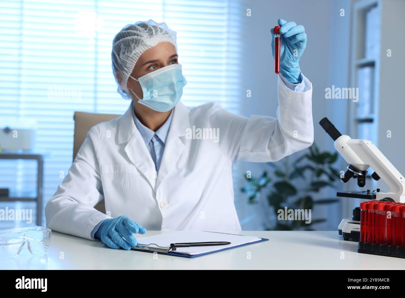 Laboratory testing. Doctor holding test tube with blood sample at table ...