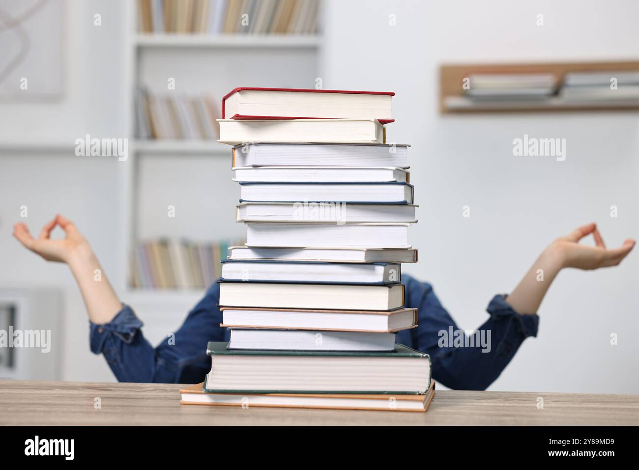 Student meditating before exam behind stack of books at table indoors ...