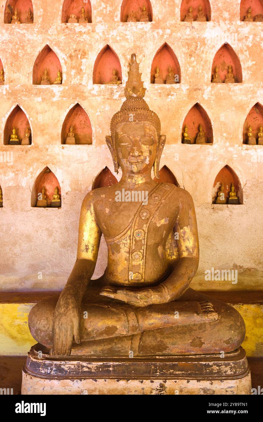 Large gold, sitting Buddha statues in front of small wall alcoves with ...