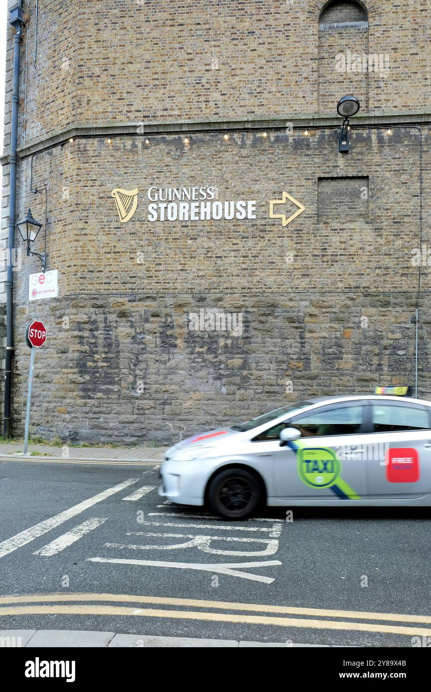 Blurred taxi at an intersection with a sign pointing to the Guinness ...