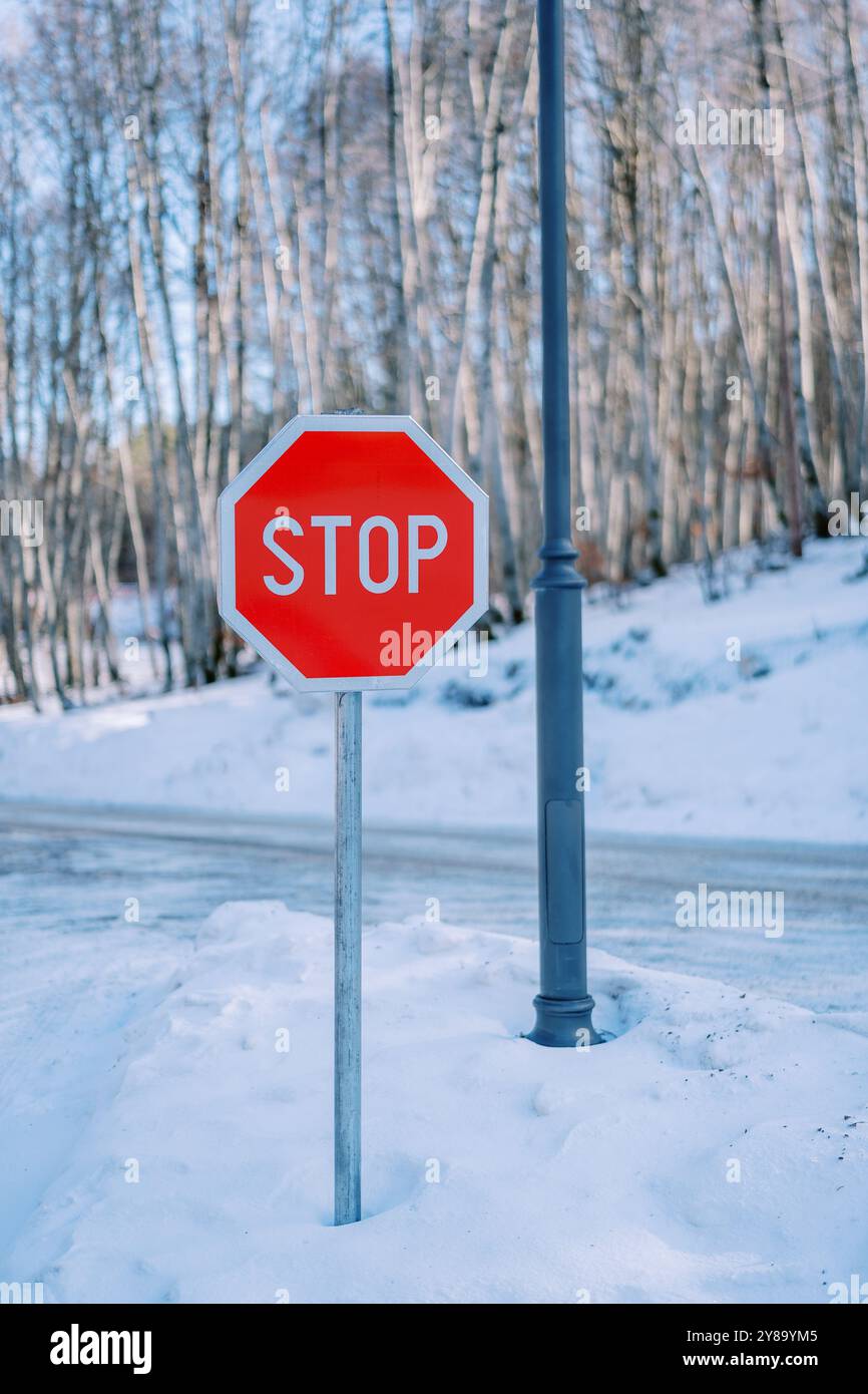 Road sign near a pillar on a snowy road in the park. Caption: Stop ...
