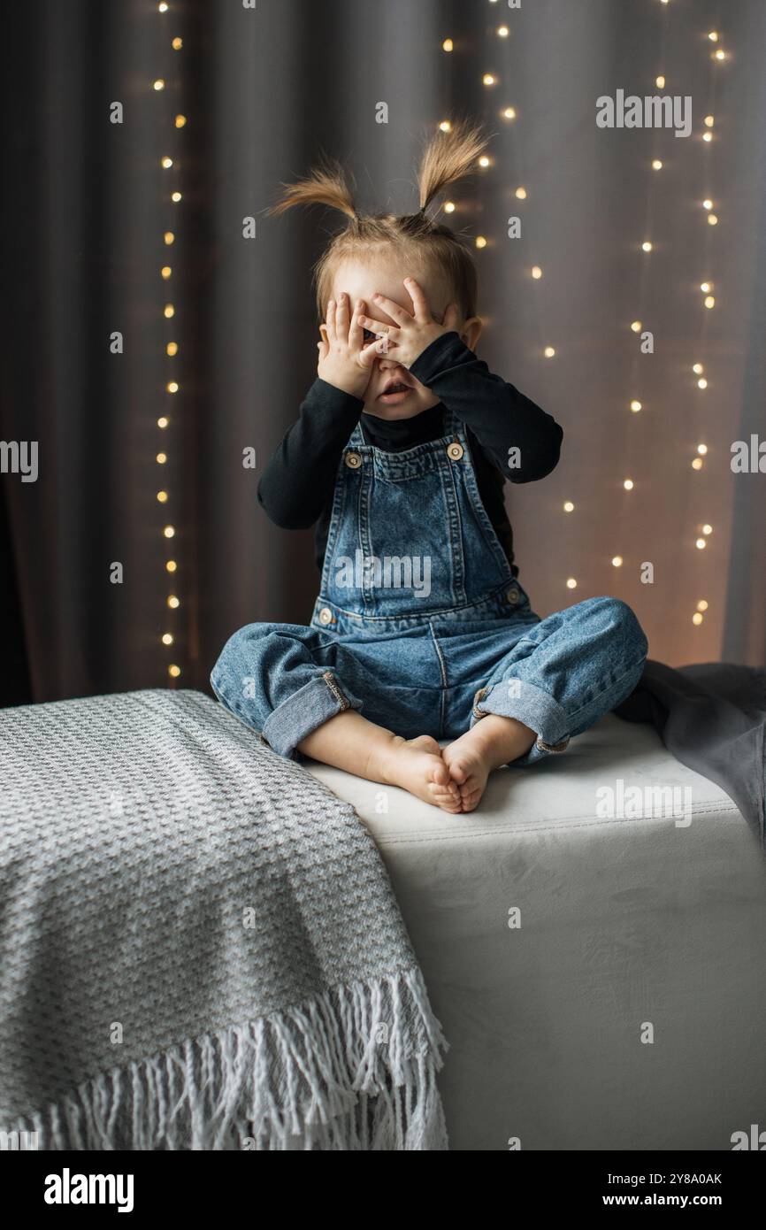 Cute child covering face with hands in playful setting Stock Photo - Alamy