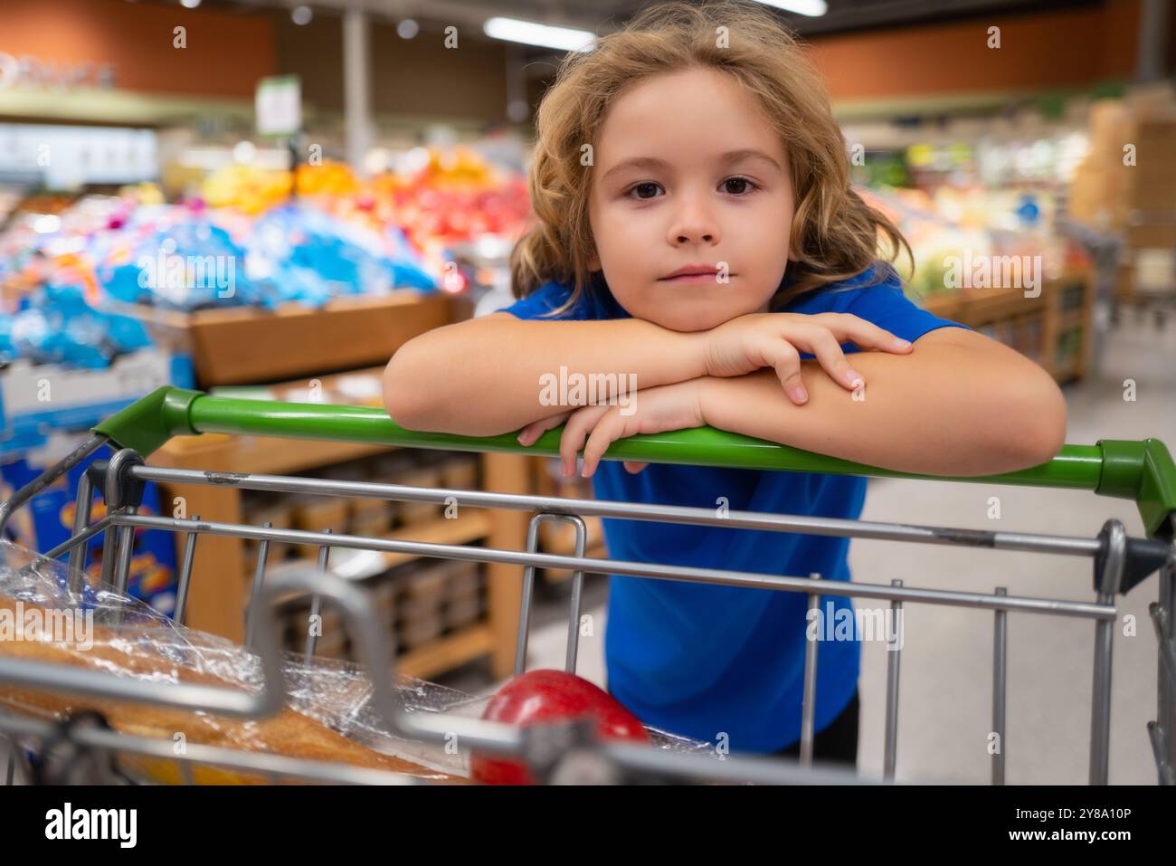 Kid with shopping cart at grocery store. Kid choosing food in grocery ...