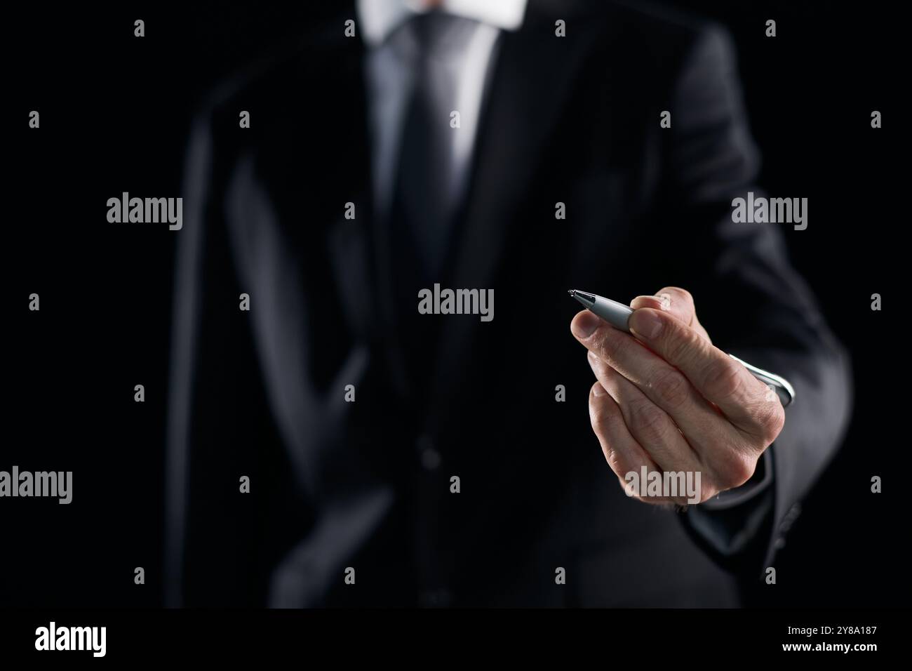 Left hand writing with marker on transparent board on black background ...
