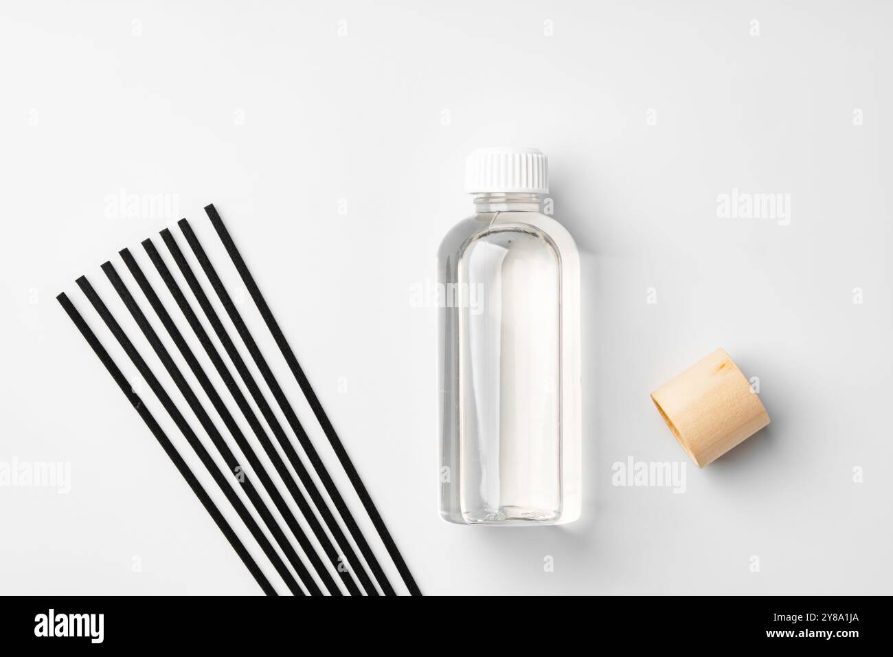 A minimalist display of essential oil and black diffuser sticks on a ...