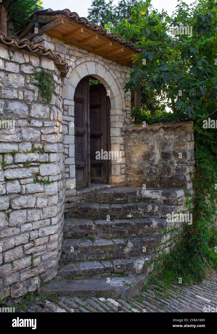 A wooden double door with steps leading to it in an historic stone ...