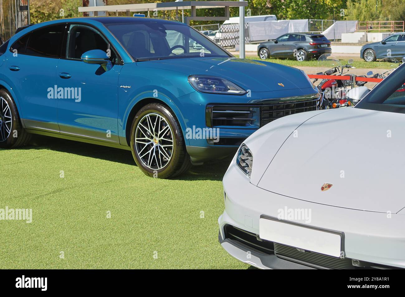Two modern porsche cars are parked on green grass during a presentation ...