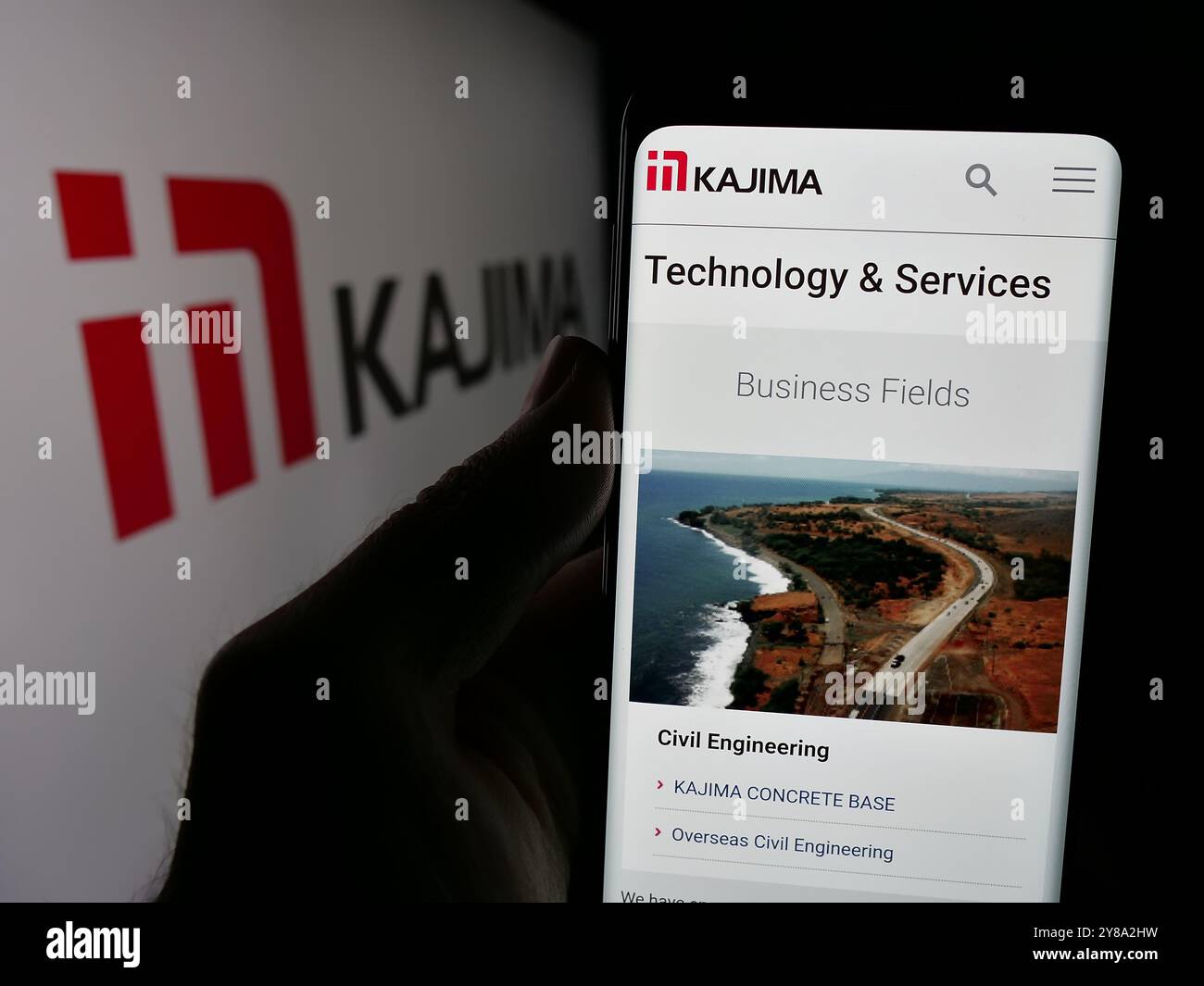 Person holding smartphone with webpage of Japanese construction company ...