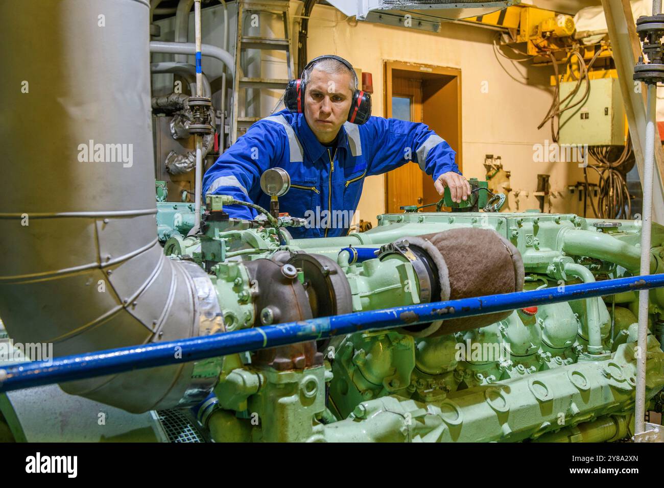 Marine Engineer in blue overall working in Engine room of ship. Work at ...