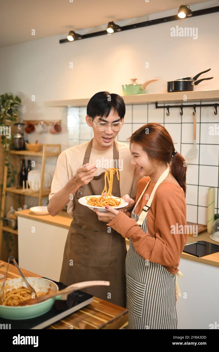 Lovely young couple sharing a plate of spaghetti, enjoying a meal ...
