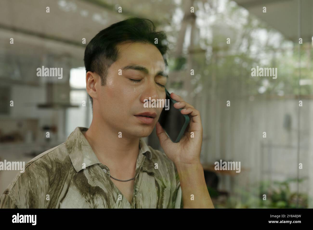 Man crying while talking on his mobile phone Stock Photo - Alamy