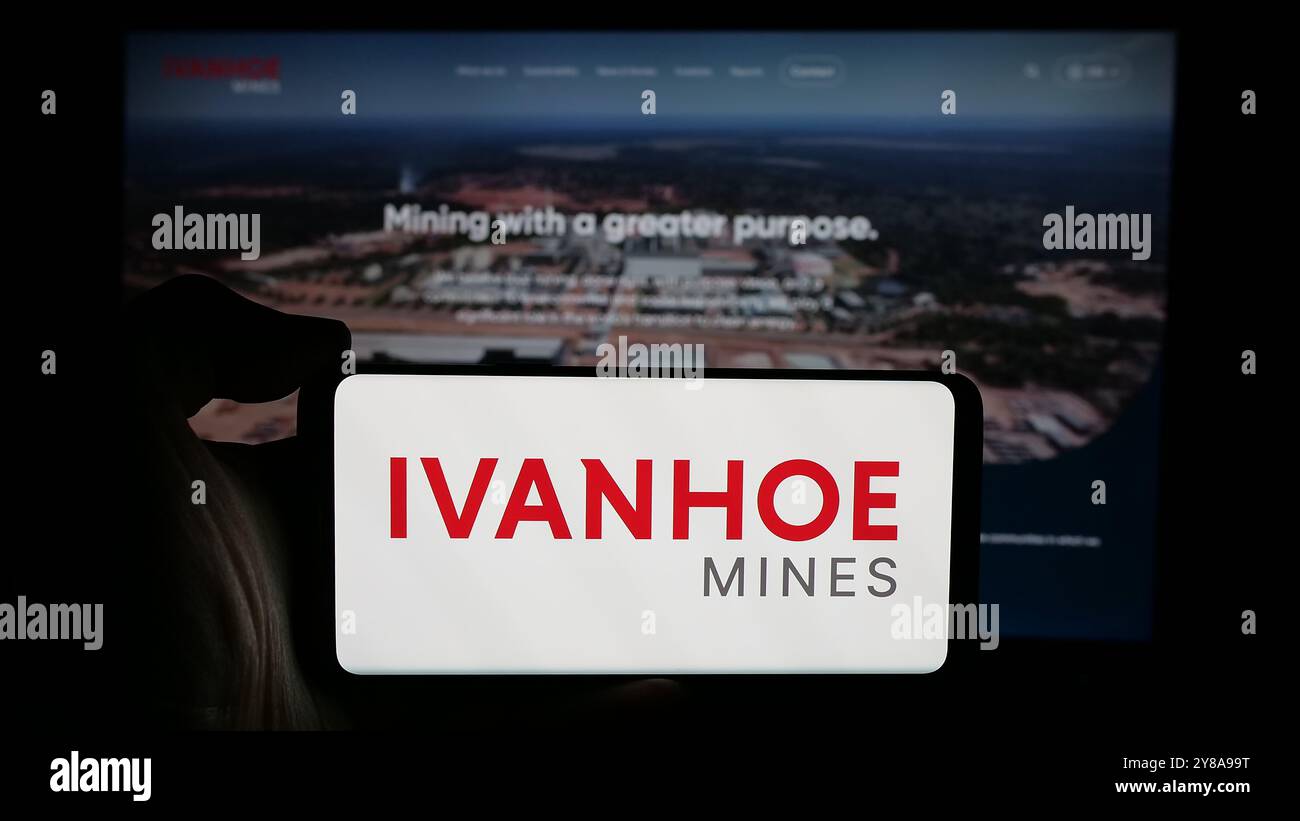 Person holding cellphone with logo of Canadian mining company Ivanhoe ...
