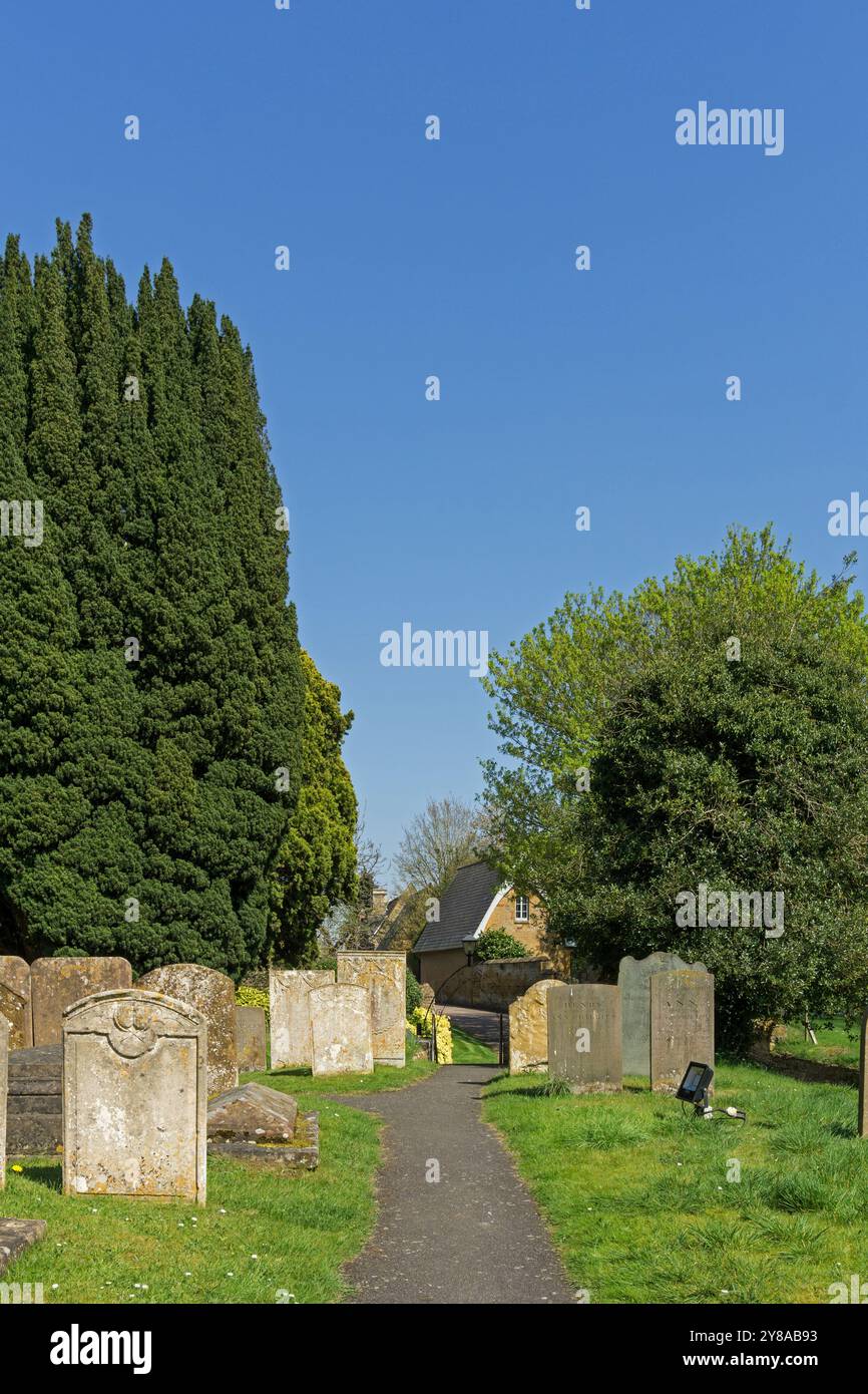 Old worn gravestones in the churchyard of All Saints in the village of ...