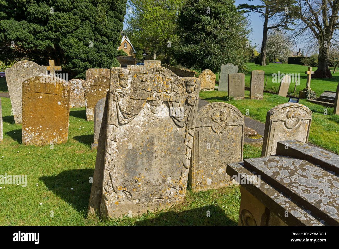 Old worn gravestones in the churchyard of All Saints in the village of ...