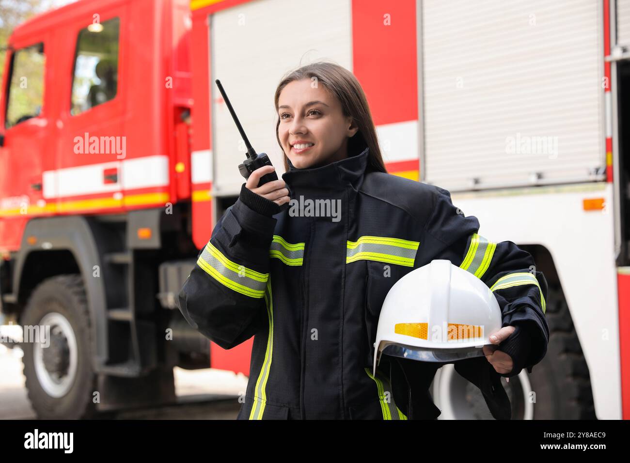 Firefighter in uniform using portable radio set near fire truck ...
