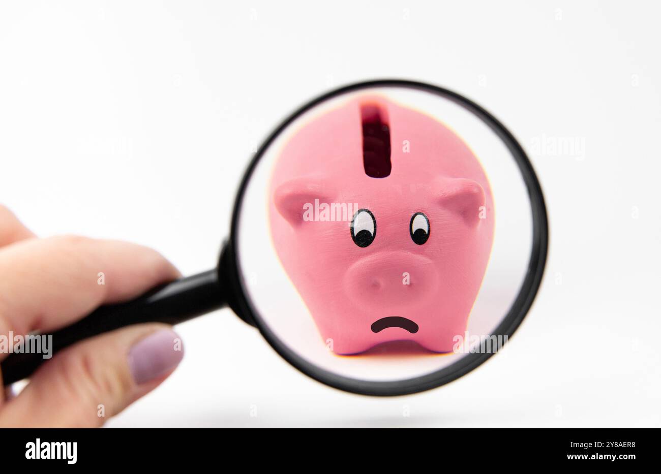 Person hand holding magnifying glass and looking at sad face piggy bank ...