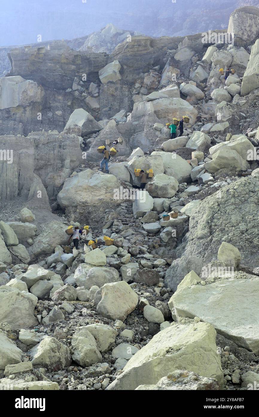 Sulfur miners climb the caldera wall of the crater of Mount Ijen, which ...