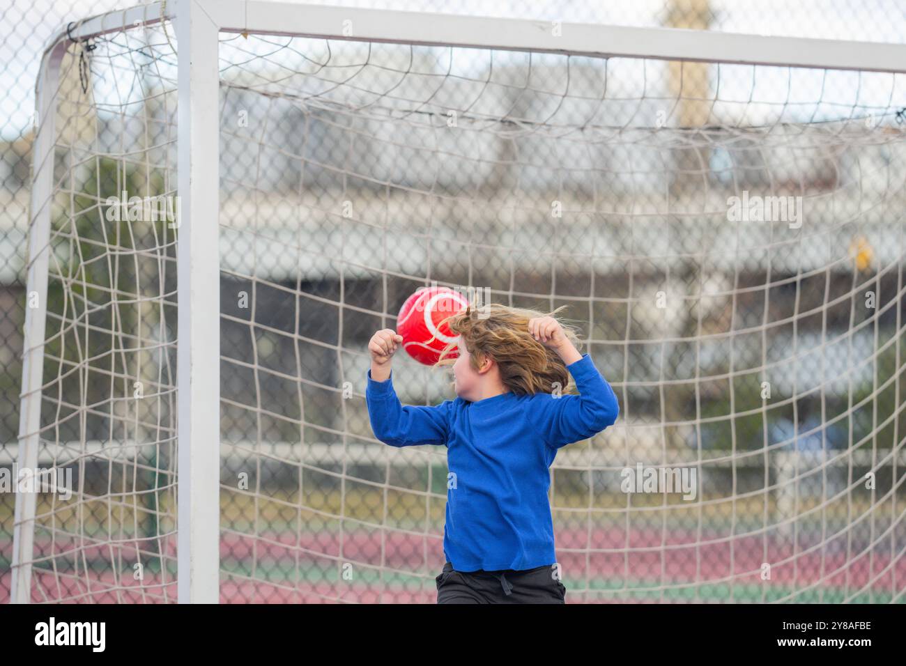 Kid Goalkeeper catches the ball in stadium during a football game ...
