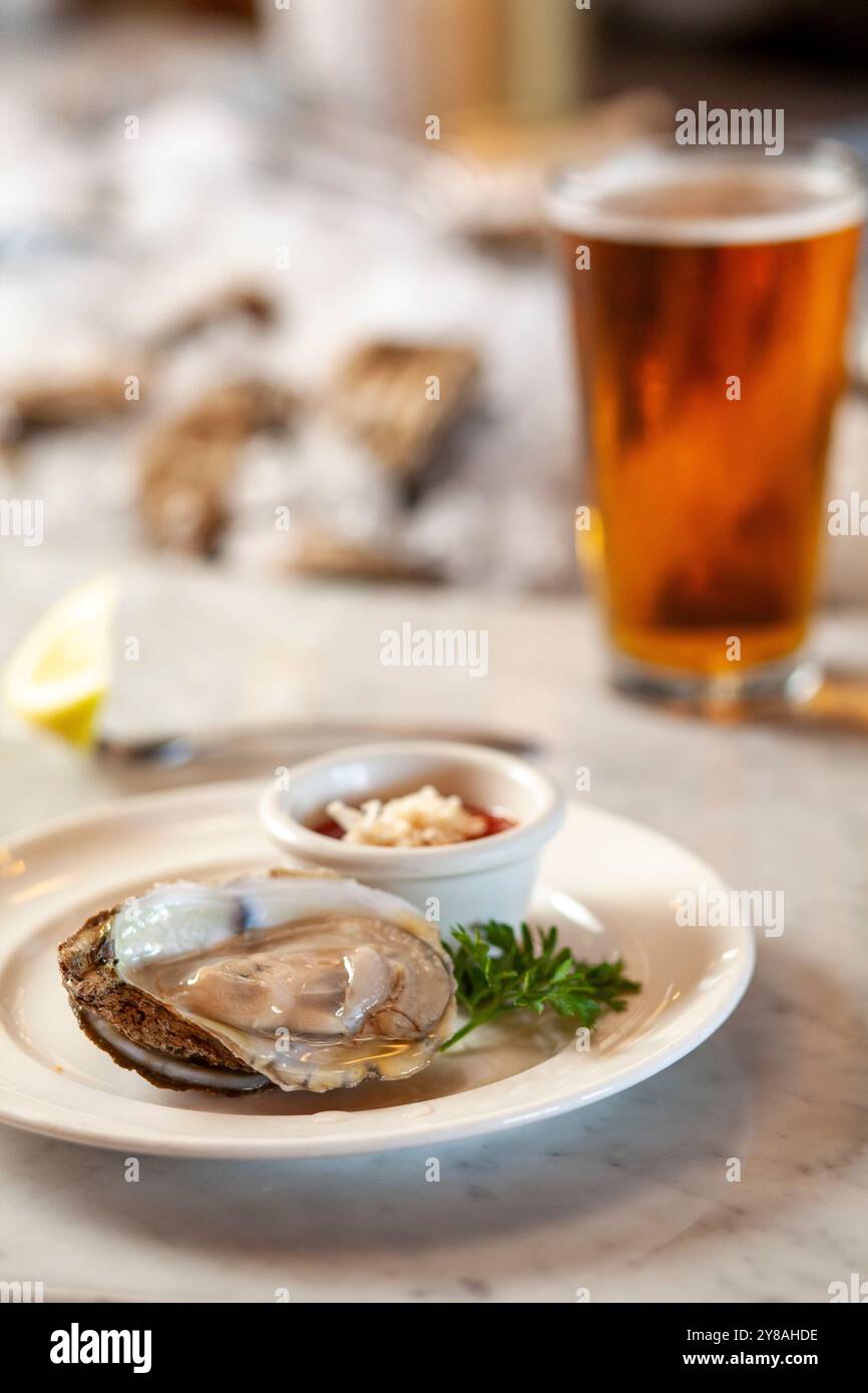 Oyster on a half shell with cocktail sauce and beer vertical Stock ...