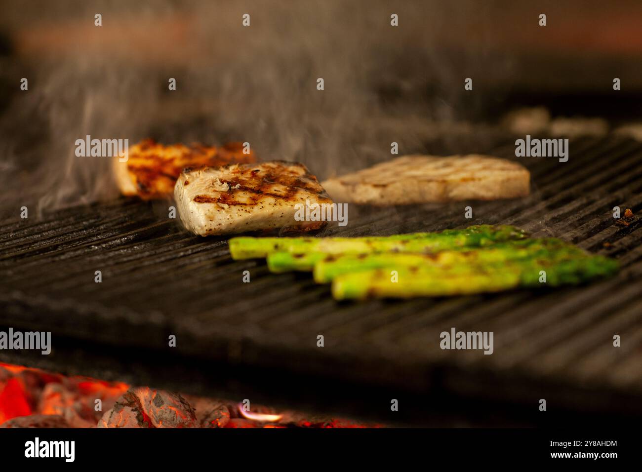 Various meats and asparagus smoking on hot grill Stock Photo - Alamy