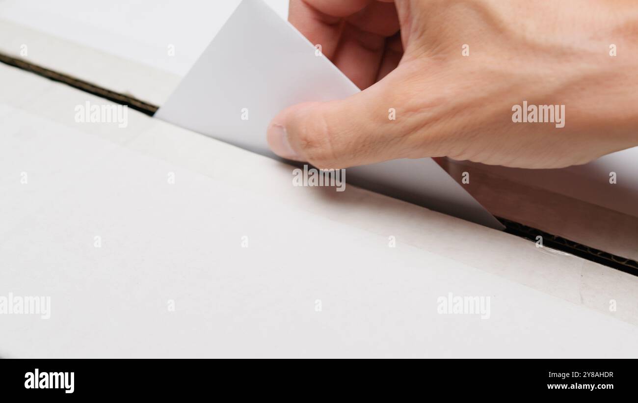 Hand inserts ballot paper into the box Stock Photo - Alamy