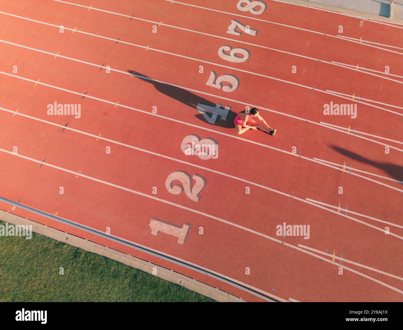 Female athlete stretching at start line on track Stock Photo - Alamy