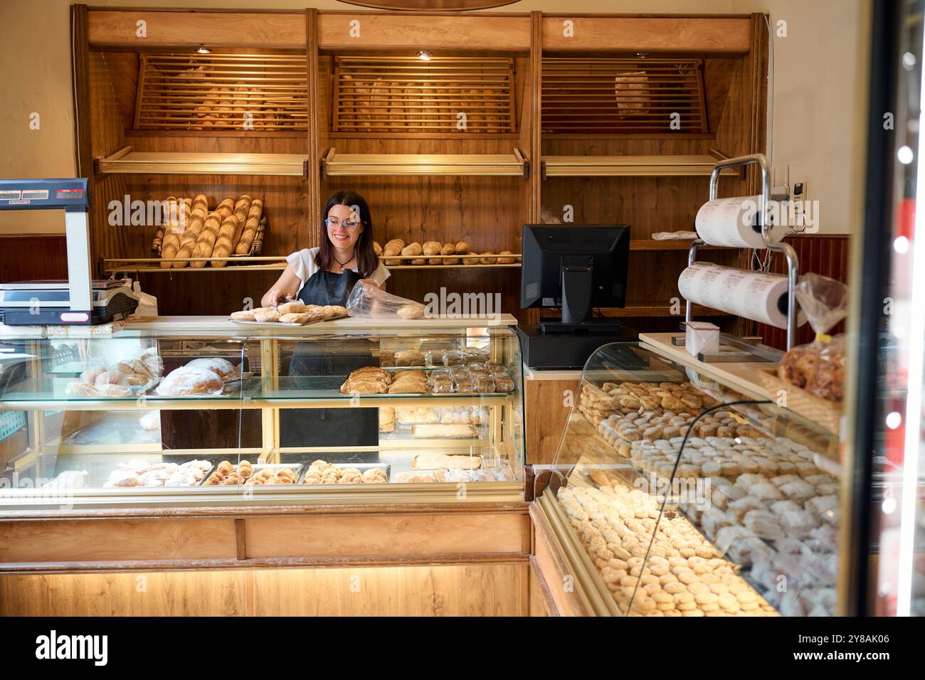Baker arranging fresh pastries in a cozy bakery during morning hours ...