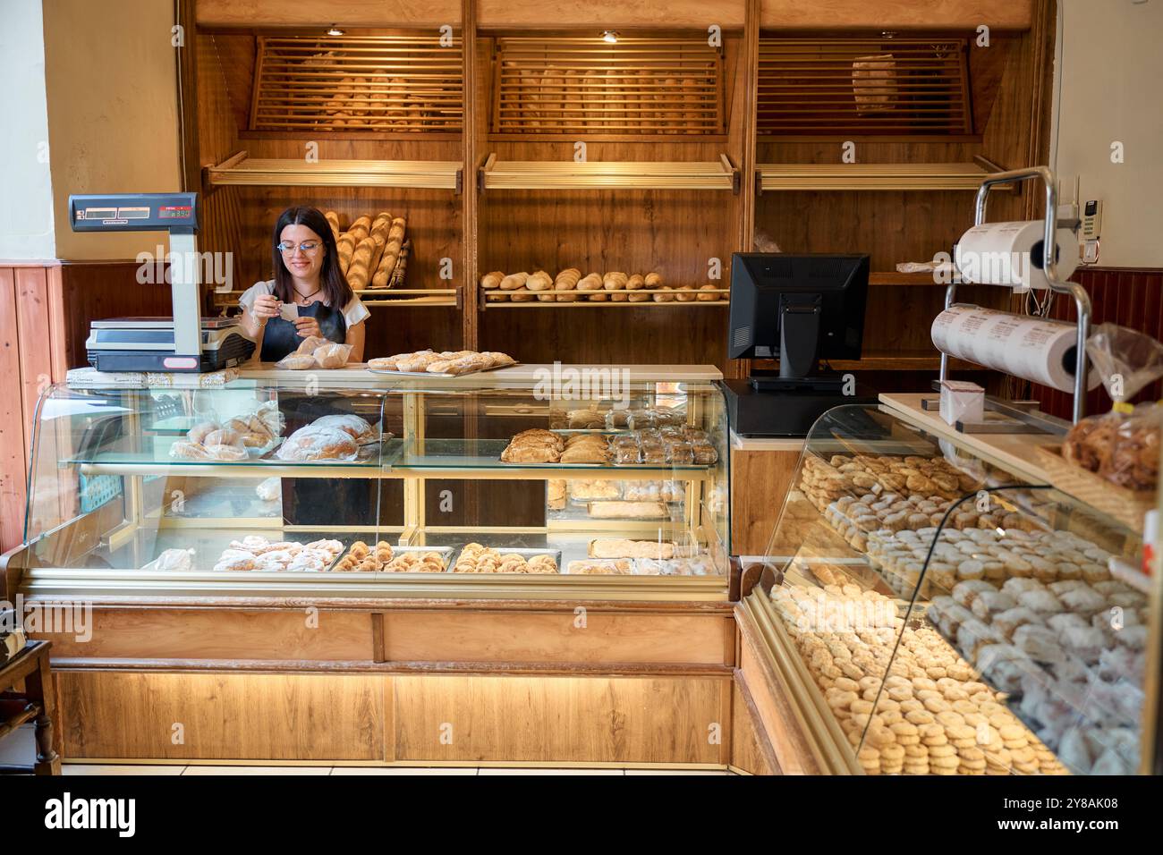 Baker arranging fresh pastries in a cozy bakery during morning hours ...