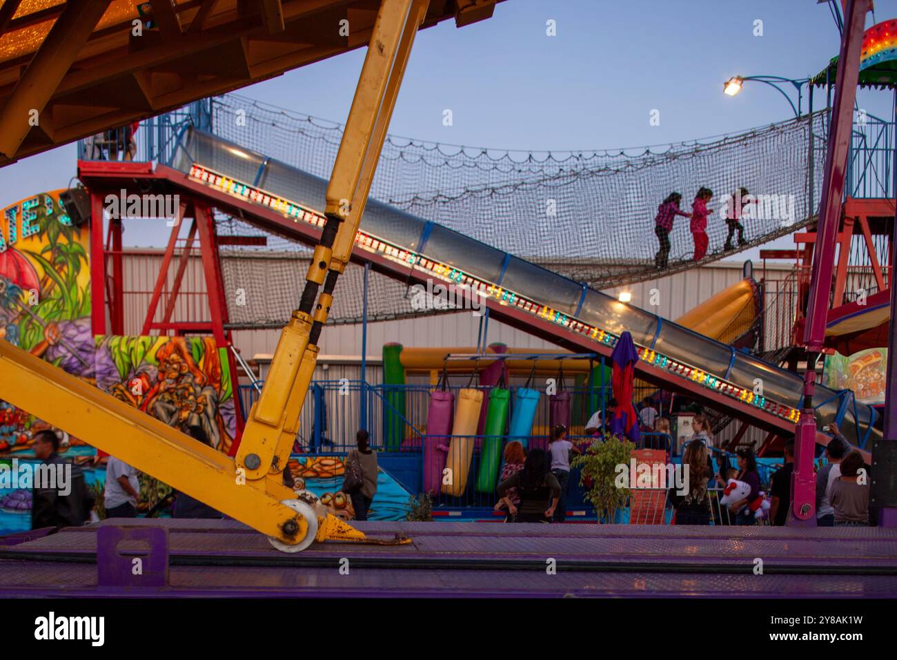 Kids play on carnival rides at state fair while adults watch Stock ...