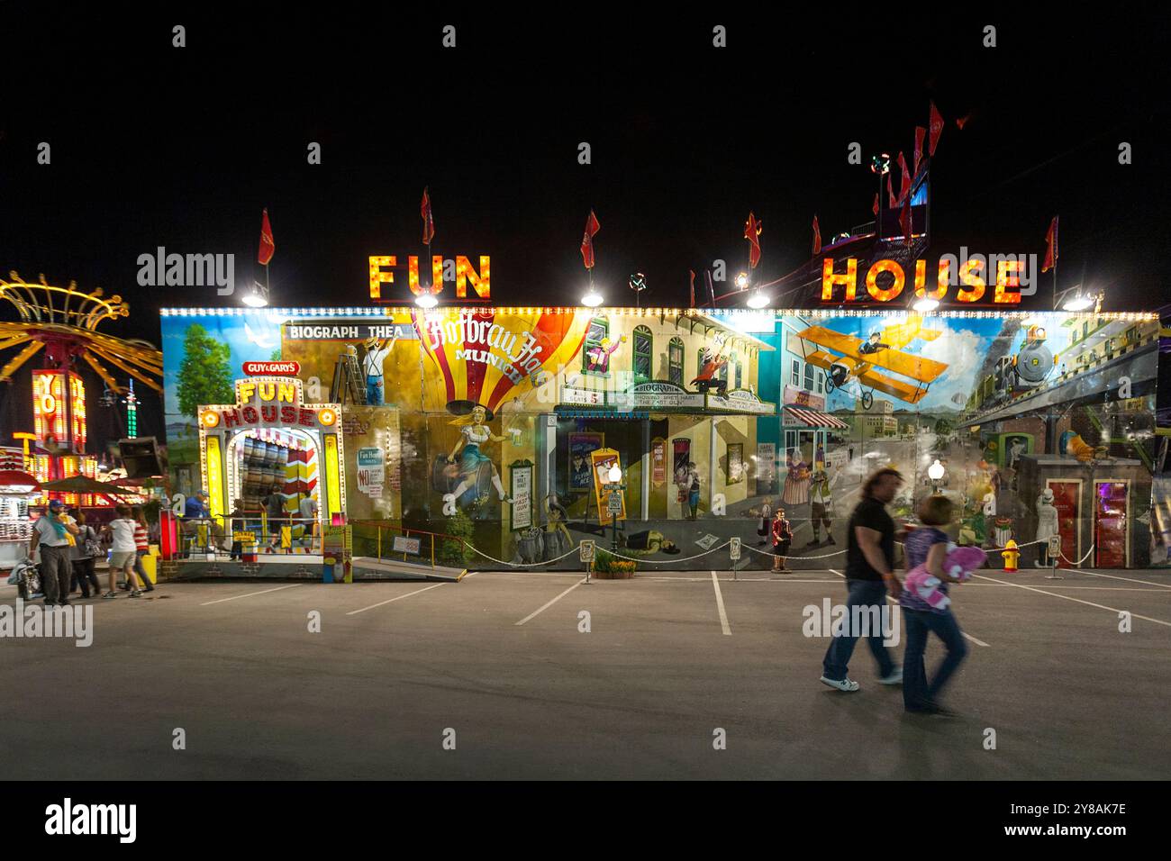 People walking past carnival fun house at night Stock Photo - Alamy