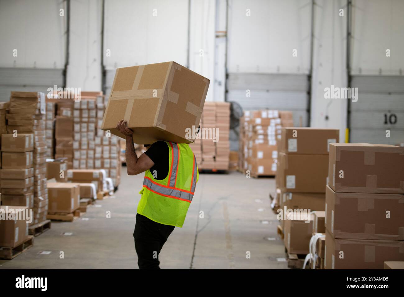 Man carrying large box on his shoulder in a shipping warehouse Stock ...