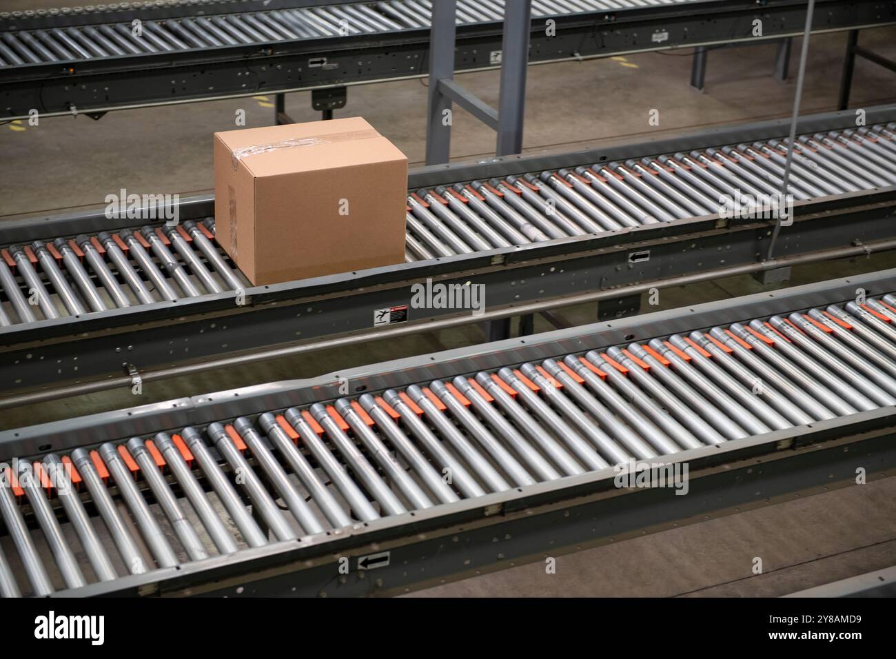 Cardboard shipping box moving through warehouse on rollers Stock Photo ...