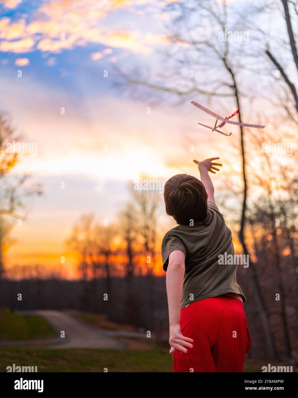 a boy launching his paper airplane into the sunset Stock Photo - Alamy