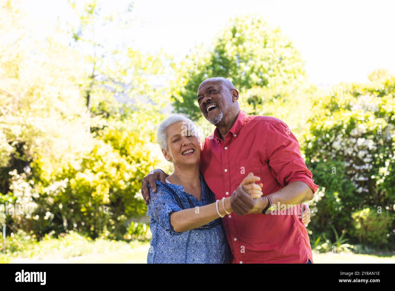 Happy diverse senior couple dancing in sunny garden Stock Photo - Alamy