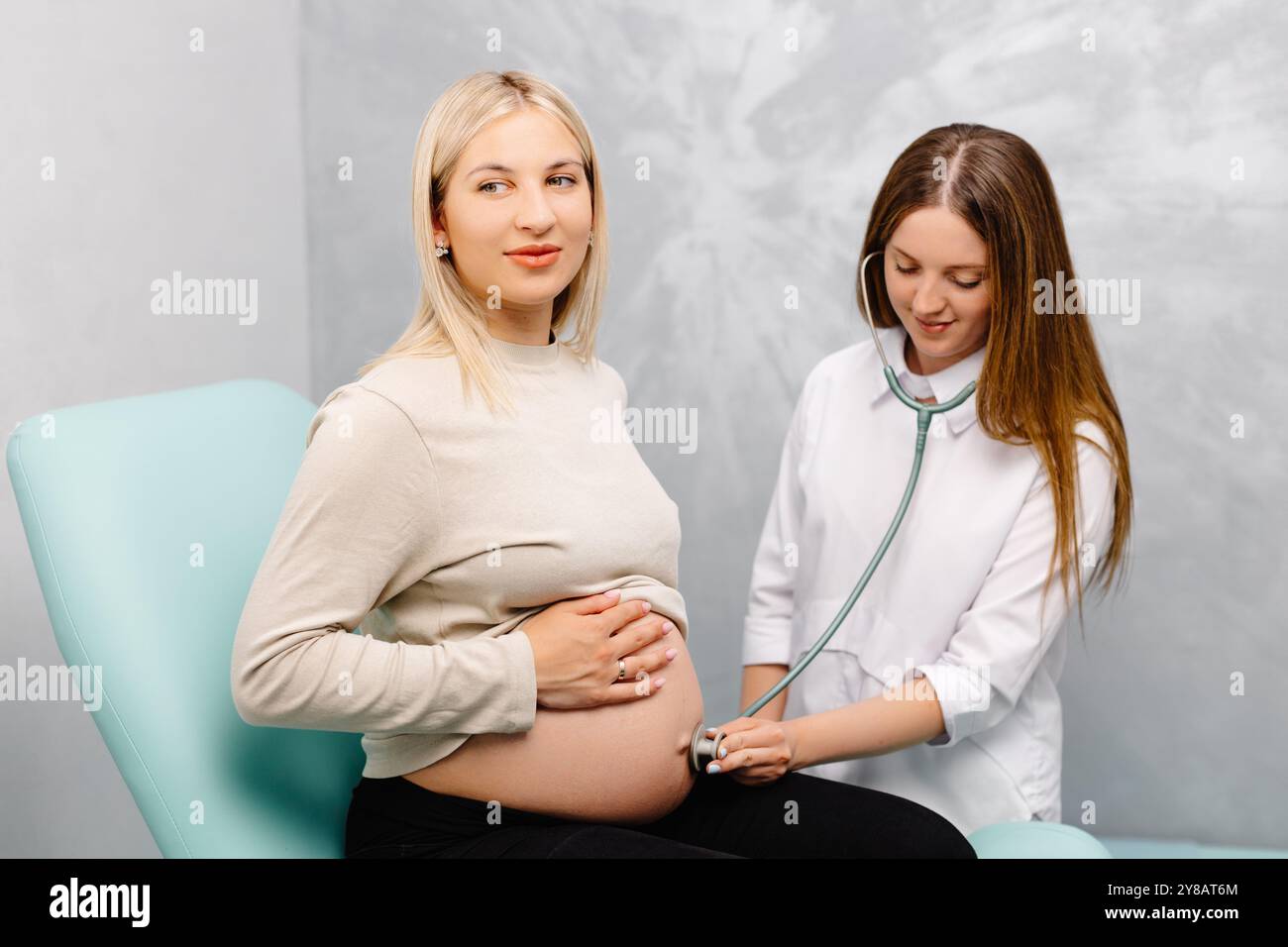 Female doctor using stethoscope examining pregnant woman in clinic ...