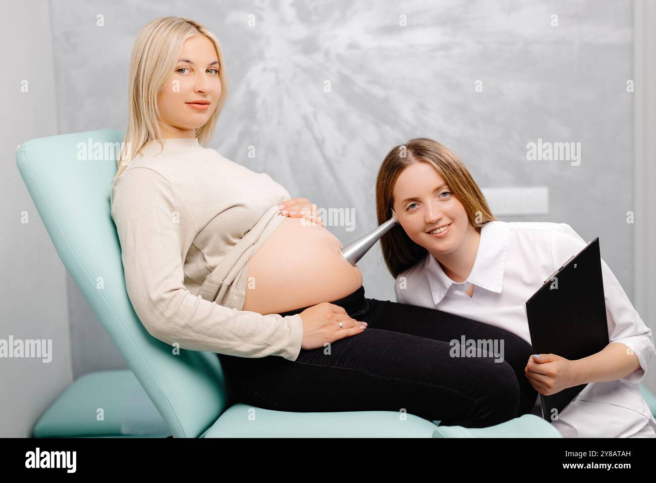 A gynecologist leans a stethoscope to a pregnant woman's belly and ...