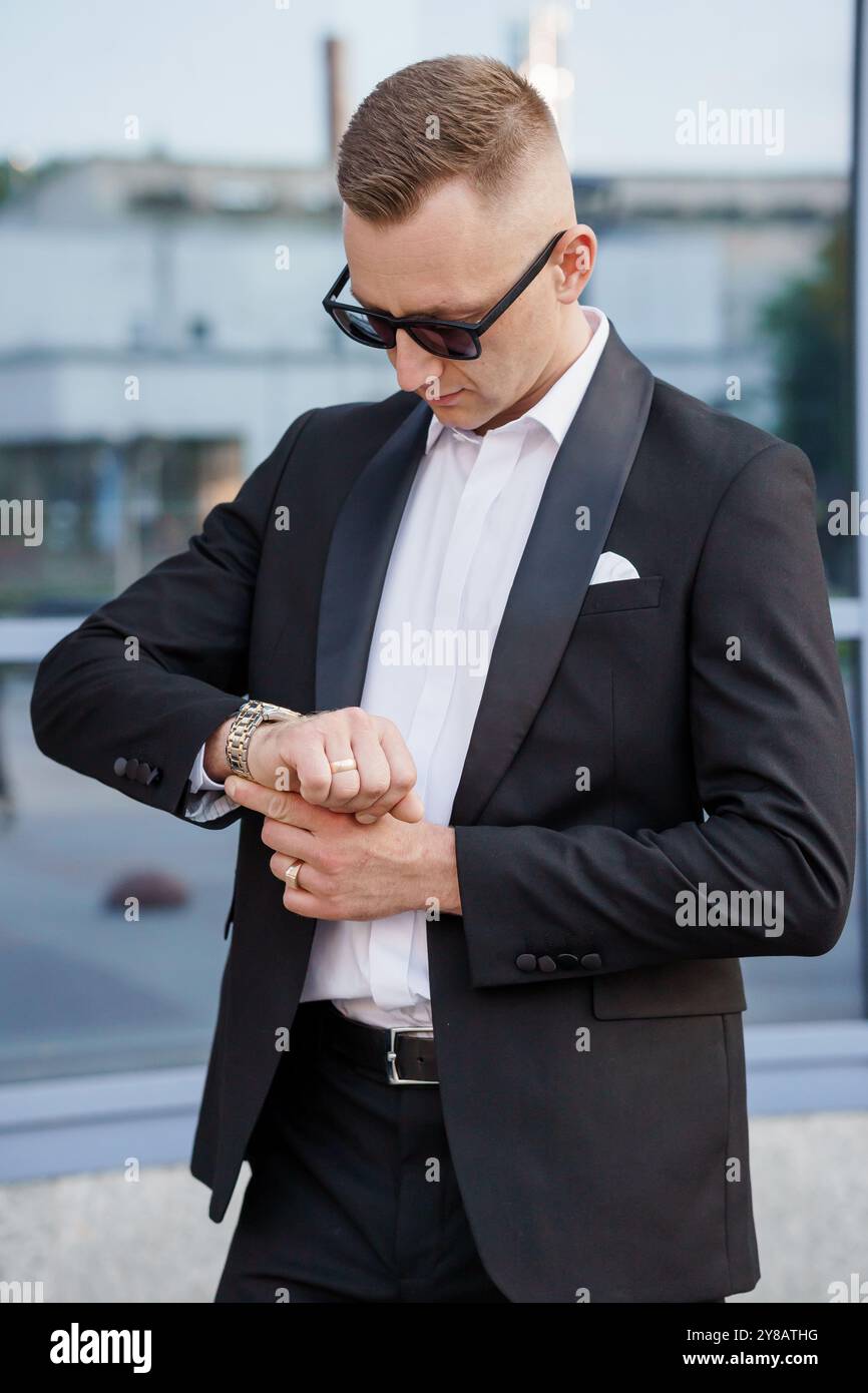 Elegant Man in Black Suit Checking Watch at Sunset Stock Photo - Alamy