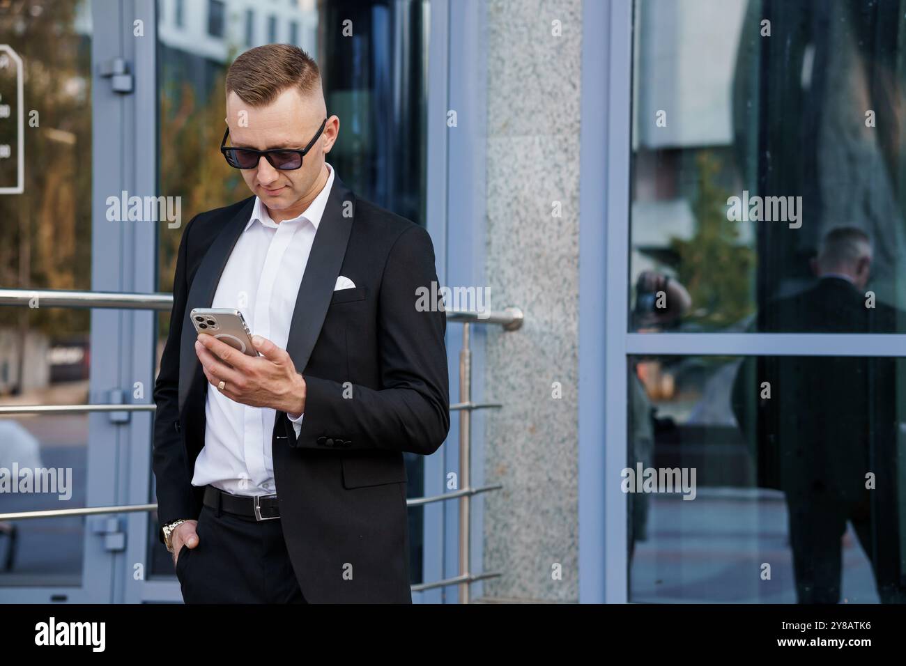 Sleek Urban Professional in Modern Attire Engaging with Smartphone ...
