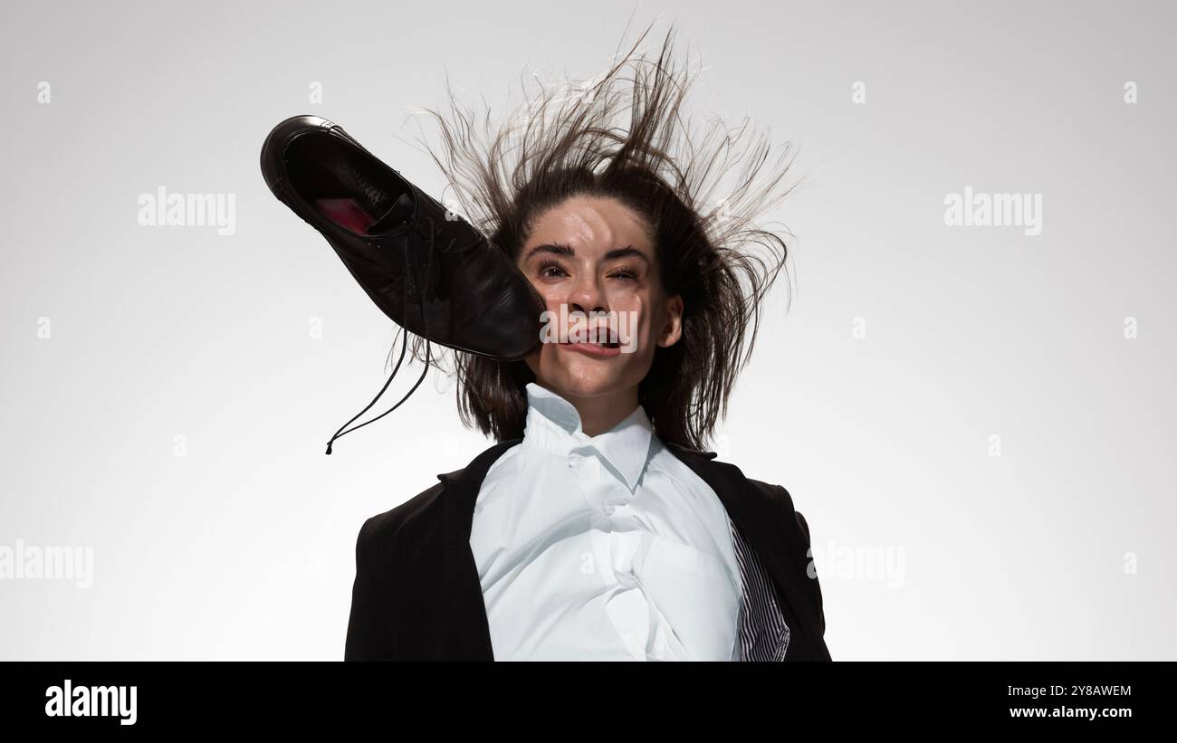 Black leather shoe smashes into woman's cheek against white studio ...